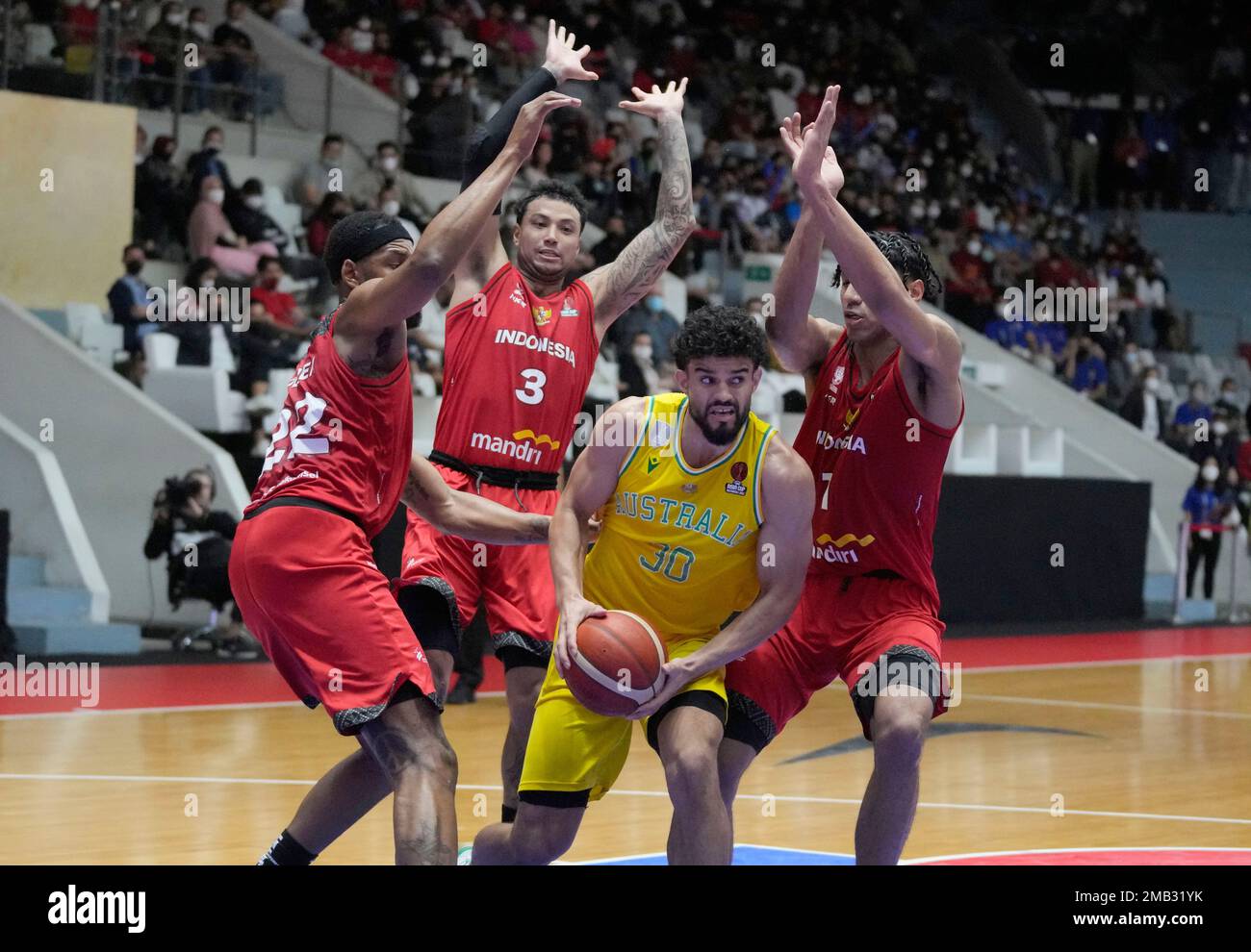 Australia's Samuel McDaniel, center, drives around Indonesia's Marques ...