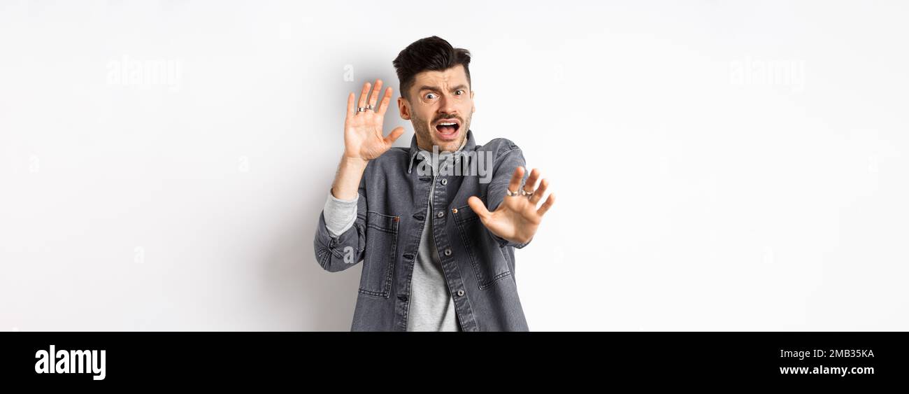 Scared timid guy screaming and raising hands in pleading pose, begging ...