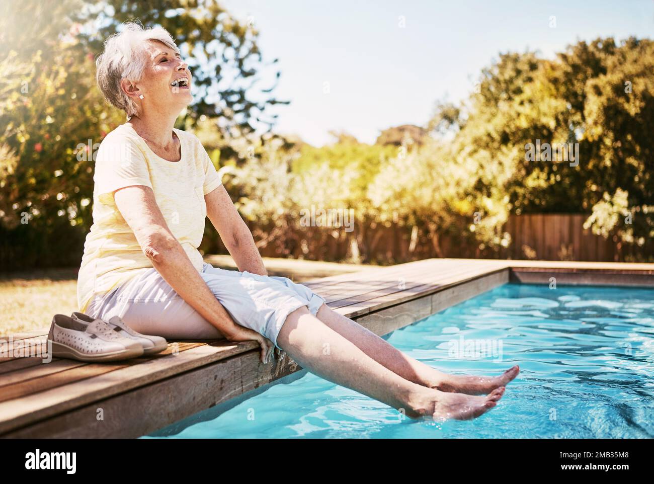 Elderly woman with her feet in the water of the pool while on a ...