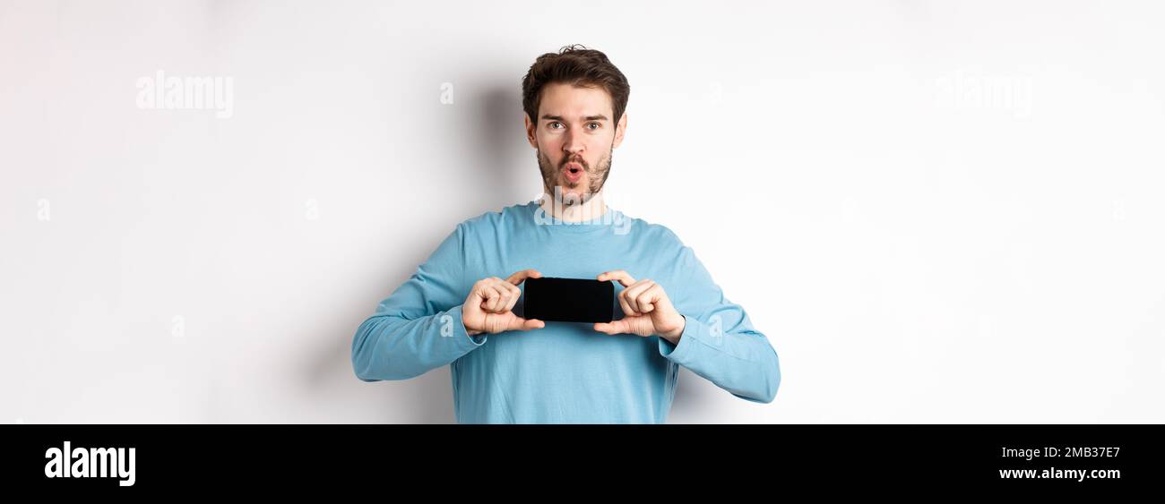 E-commerce and shopping concept. Image of impressed man saying wow and ...