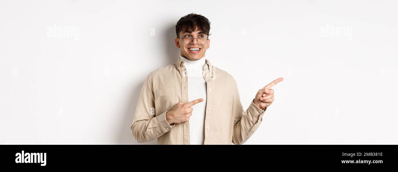 Excited and enthusiastic young man in glasses, pointing fingers and ...
