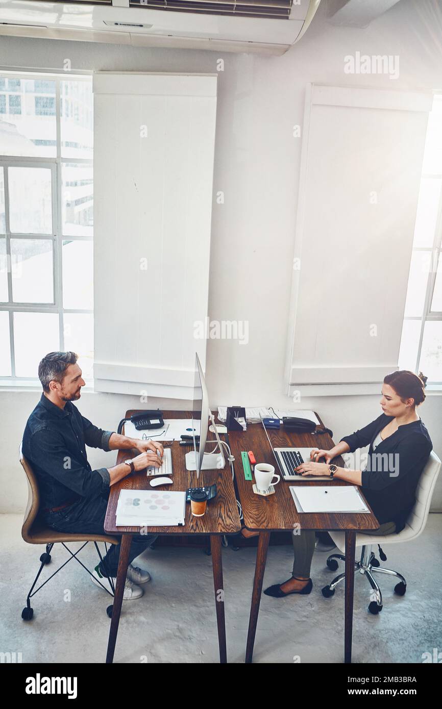 Laptop, computer and business people with opposite desk in office ...