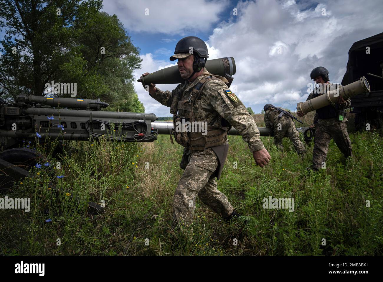 A Ukrainian serviceman carries a 155 mm artillery shell before firing ...