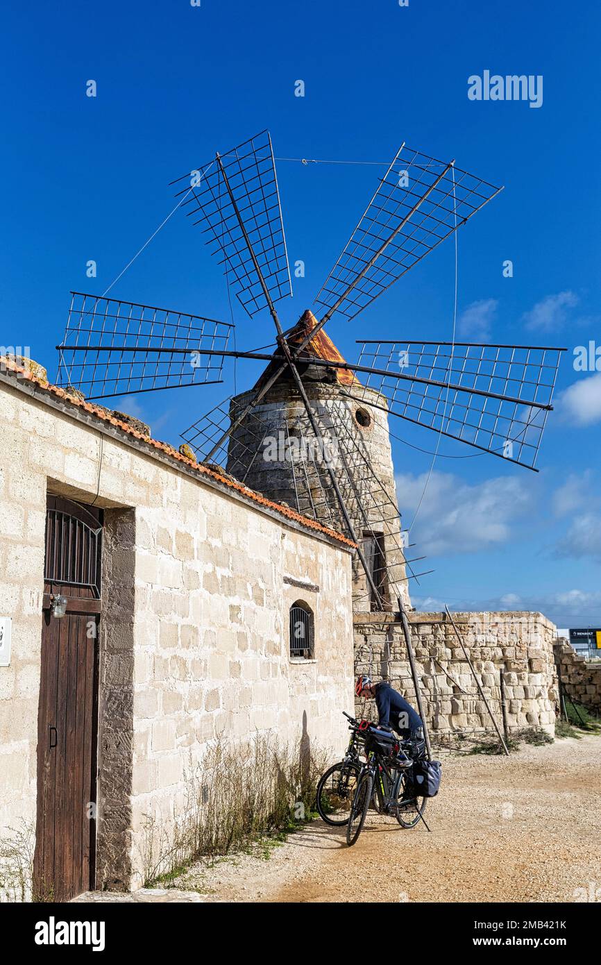 Traditional windmill for salt extraction, cyclist, tourist in front of ...