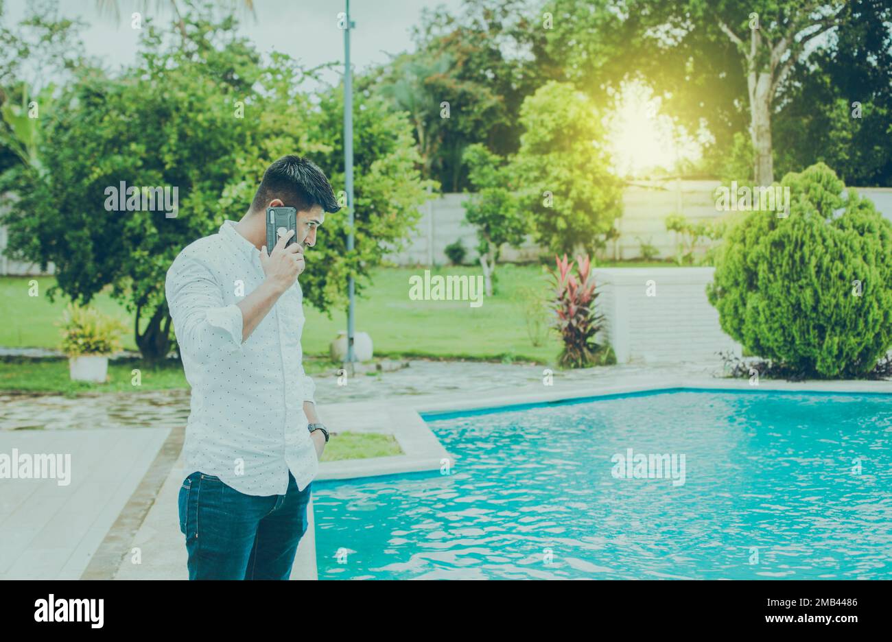 Handsome man calling on the phone by a swimming pool, Young man ...