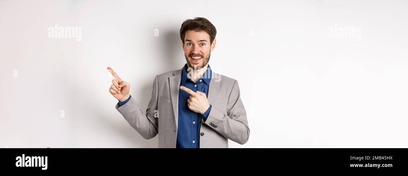 Happy businessman in suit pointing fingers right and smiling excited ...