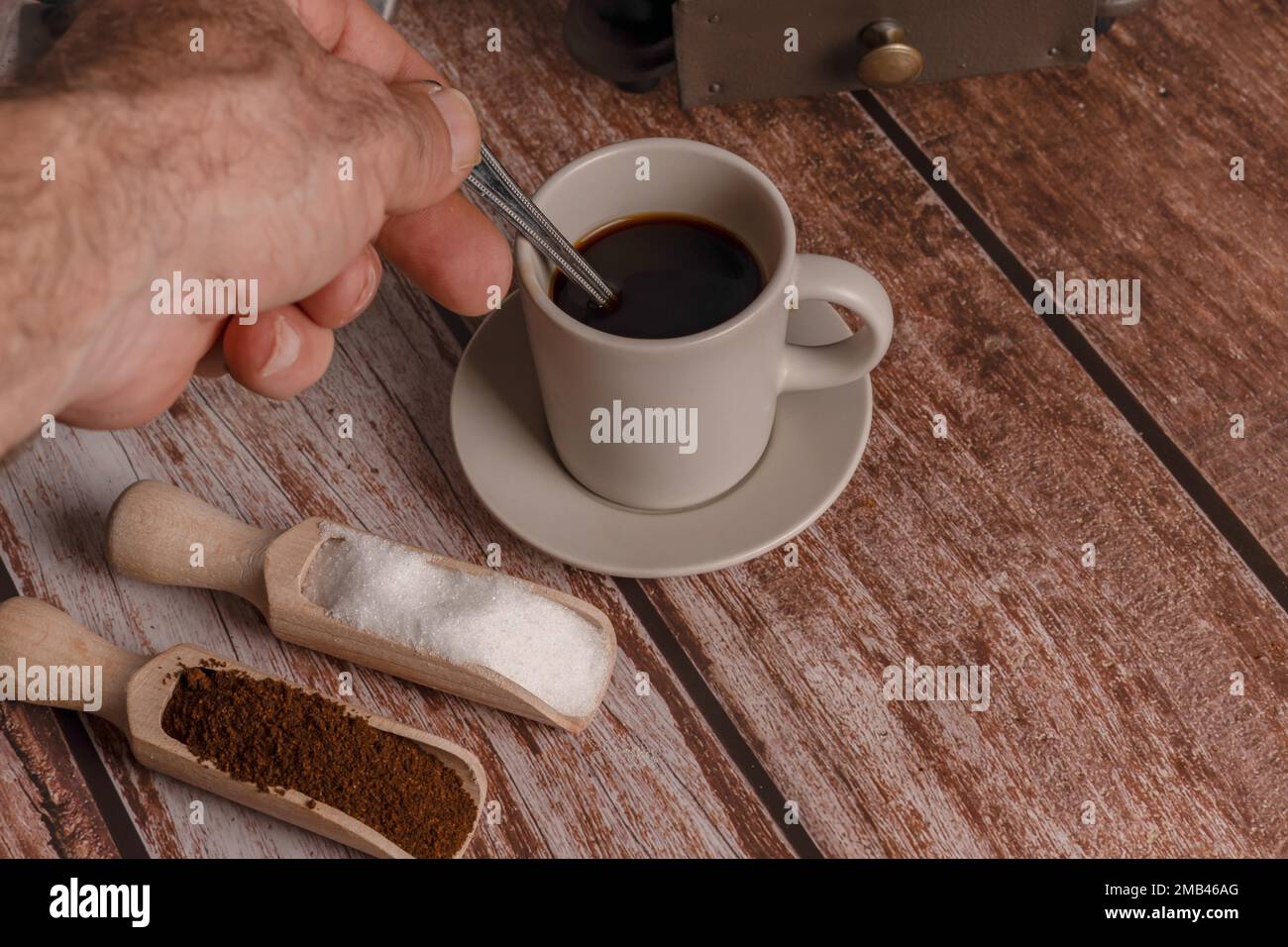 Man's hand with a spoon twirling coffee with two wooden spoons with ...