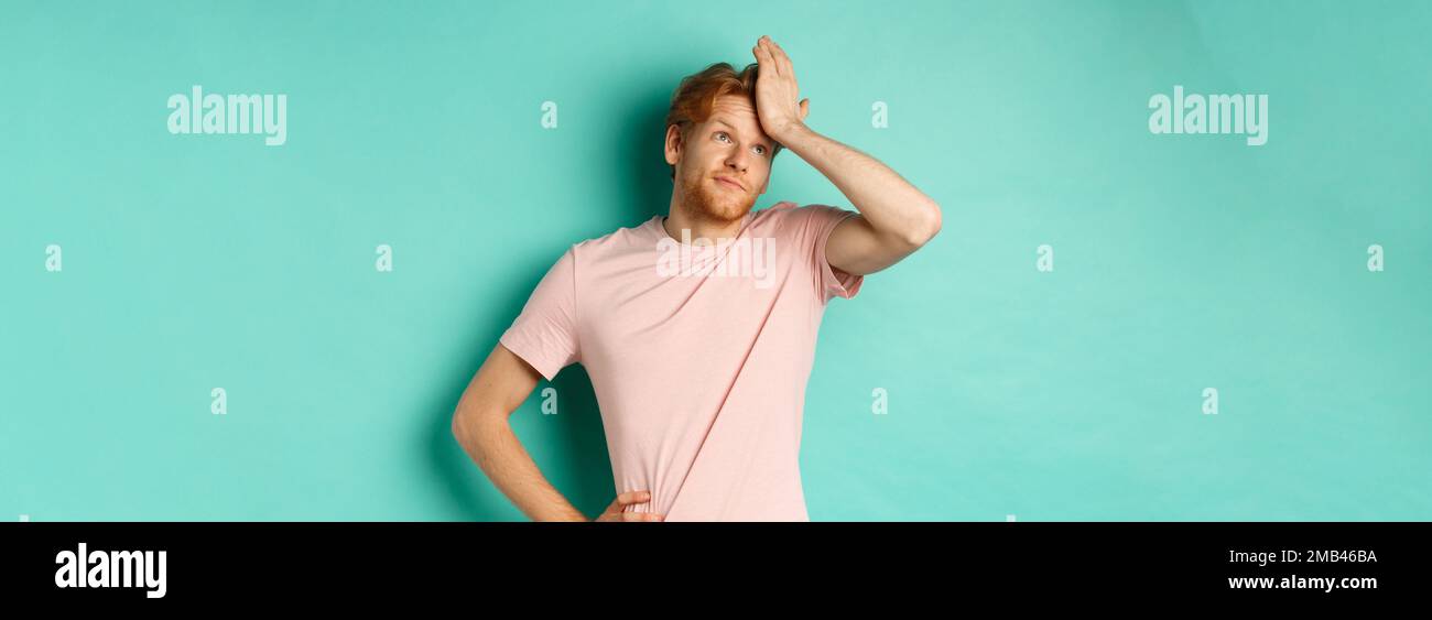 Annoyed and bothered redhead male model showing facepalm and roll eyes ...