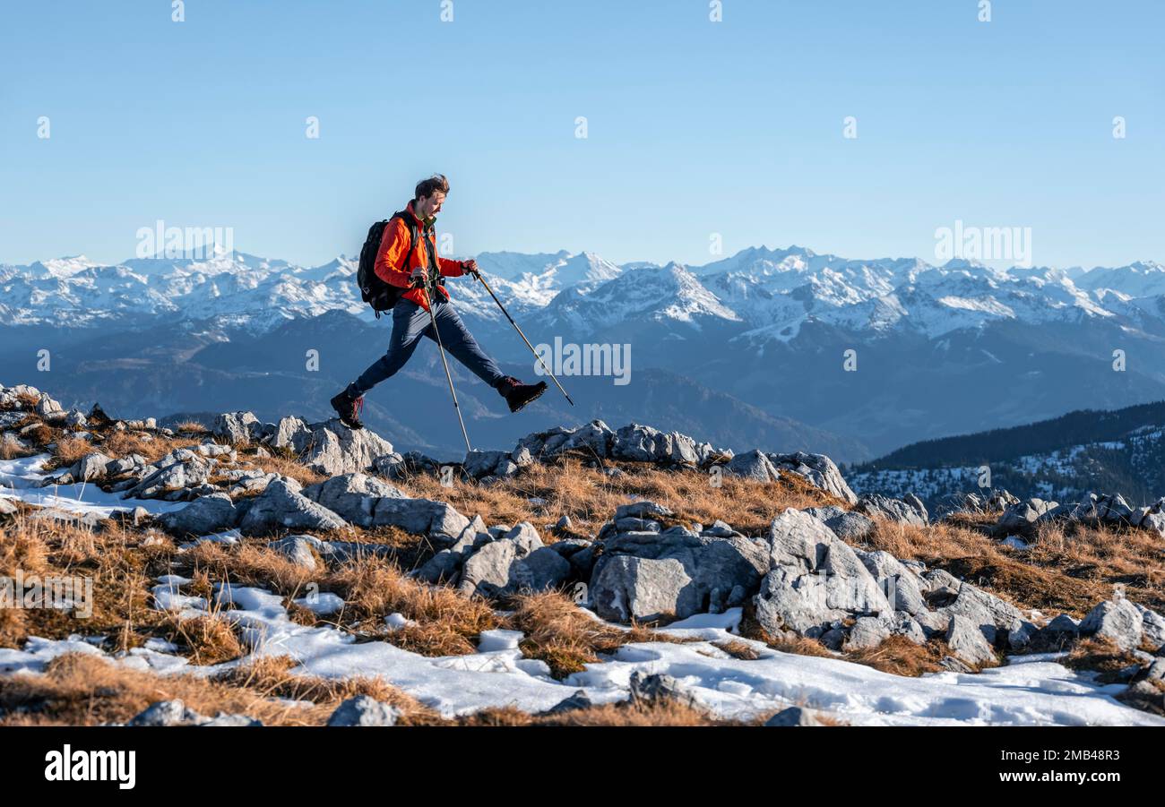Mountaineer taking a big step, in front of mountain panorama, hiking ...