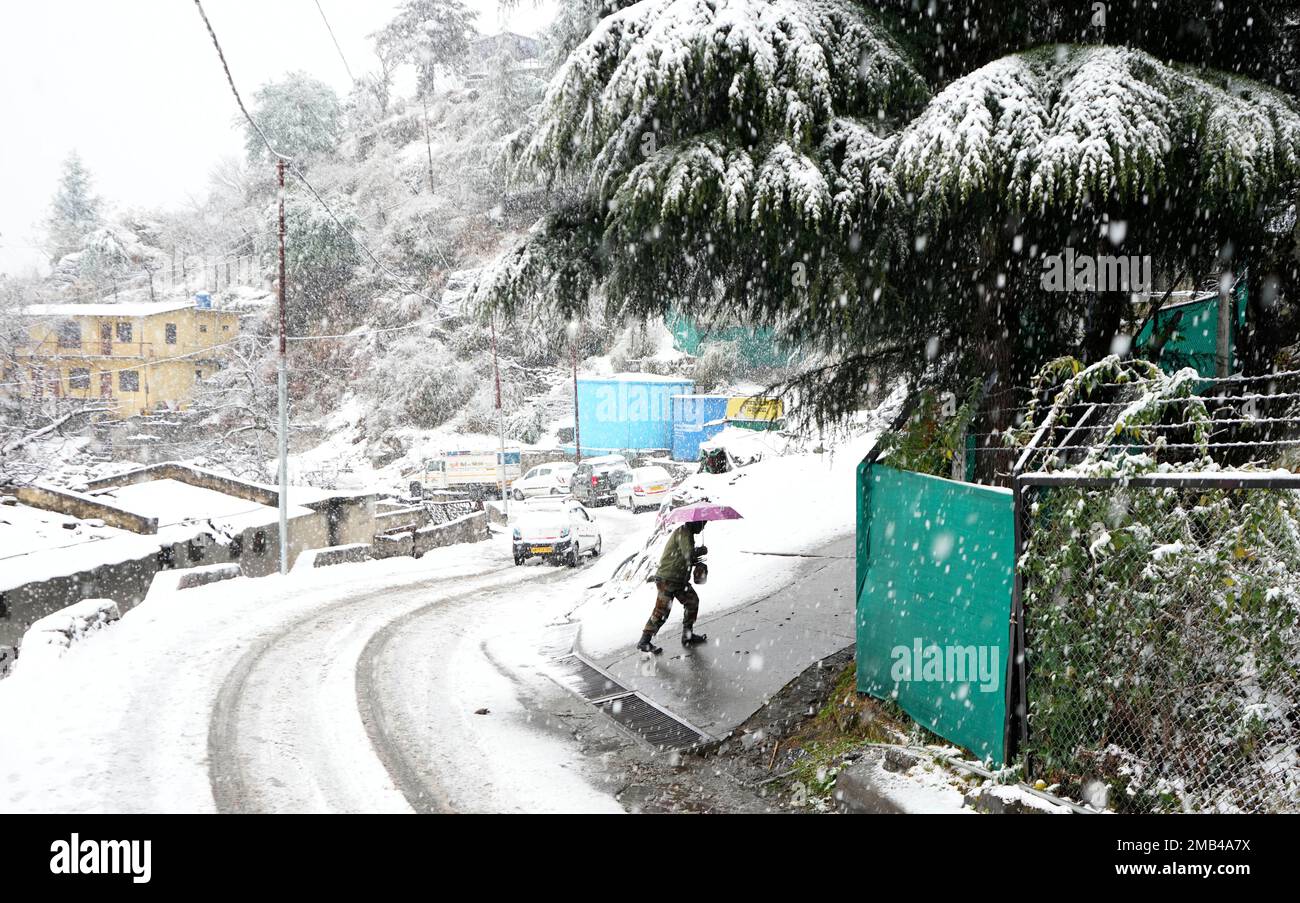 A man walks with an umbrella as it snows in Joshimath, in the northern Indian state of ...
