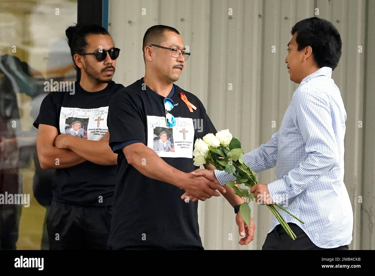 A man carrying flowers is greeted at a private viewing and funeral ...