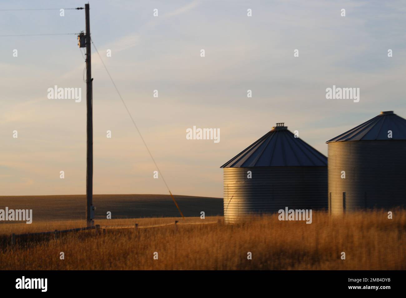 Two huge grain storage silos in a field covered in the grass under the ...