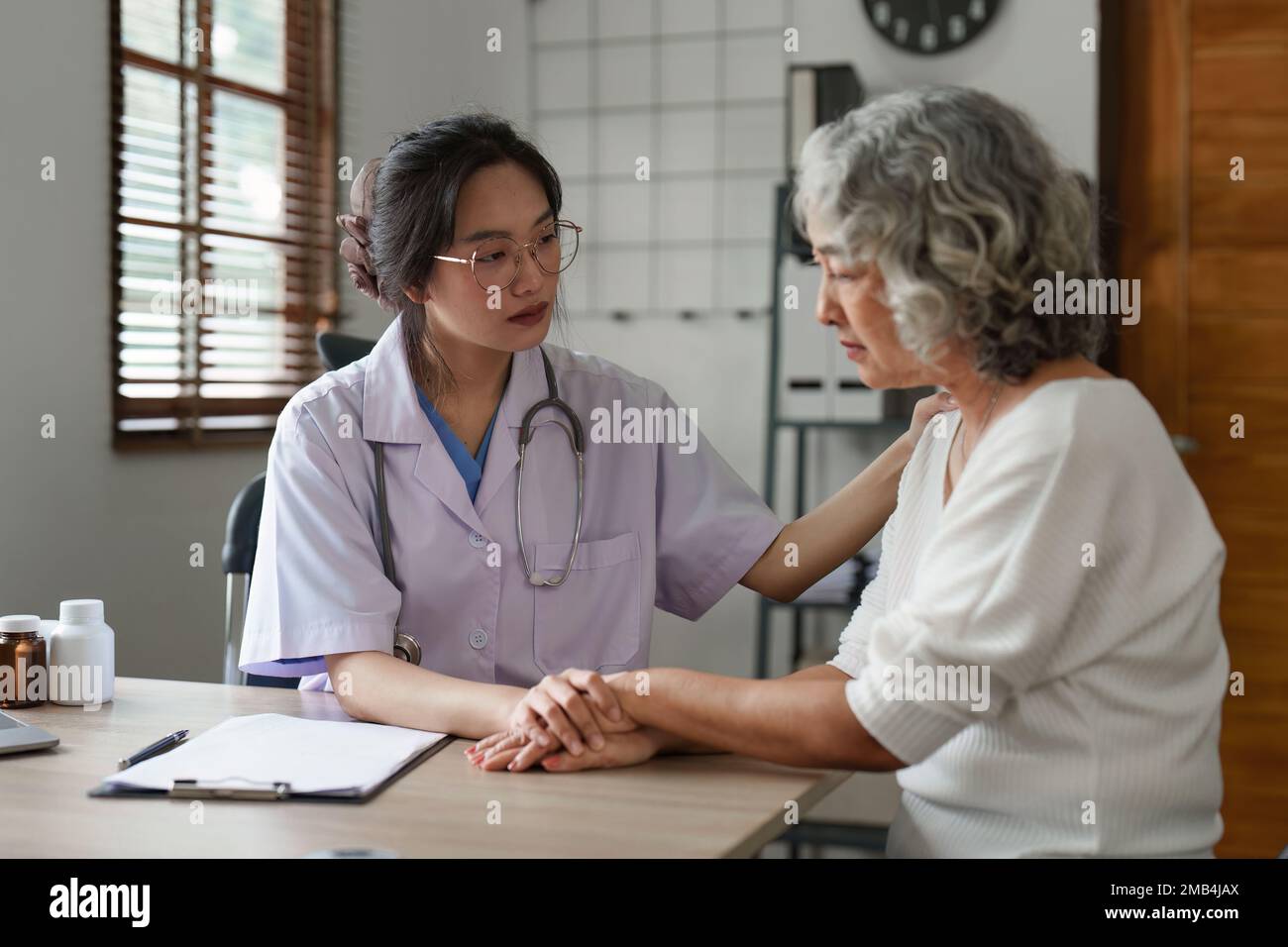 Doctor talking with elderly asian woman. Female primary care physician ...