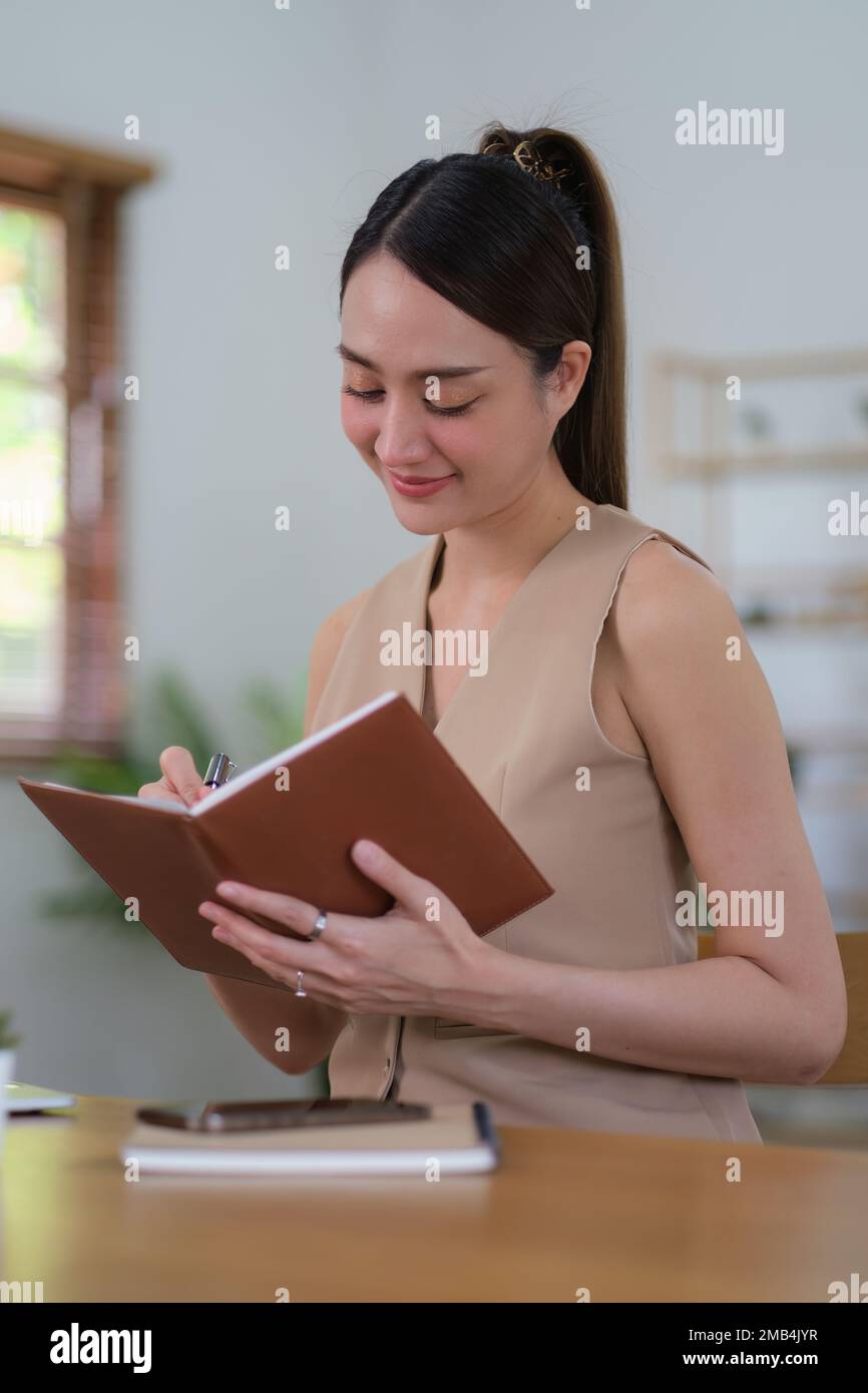 Portrait of Asian woman reading a book beside the window after get up ...