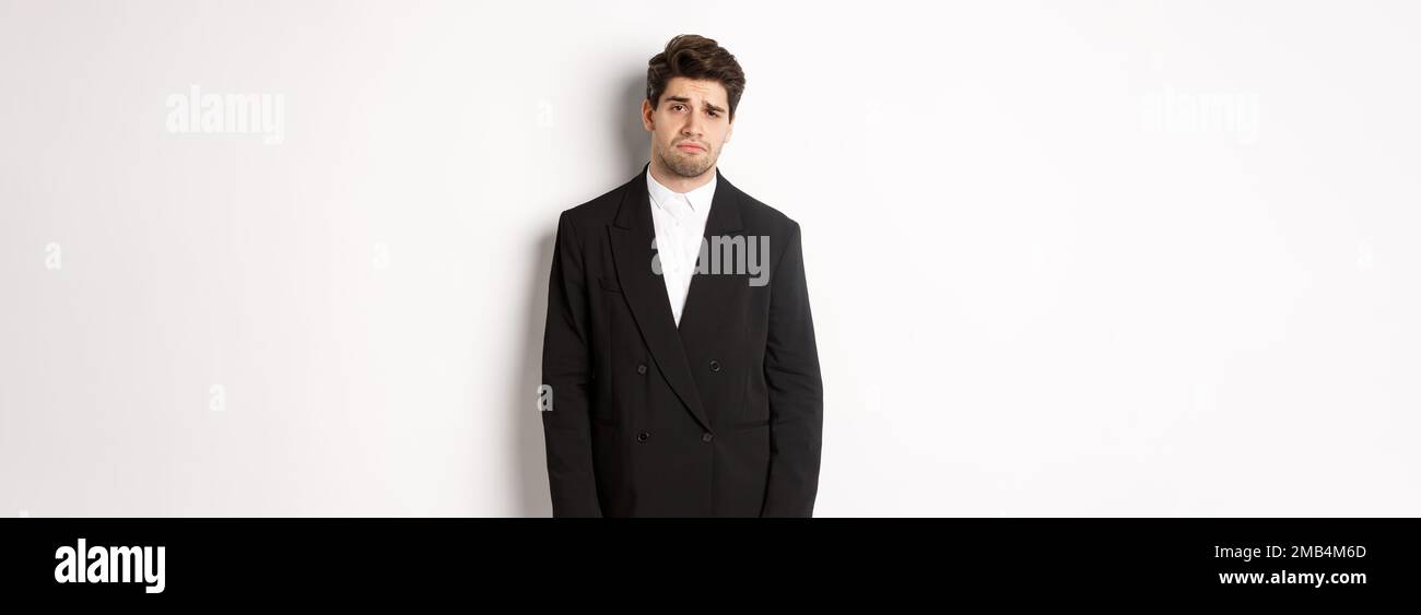 Image of gloomy and sad handsome male model in black suit, frowning and ...