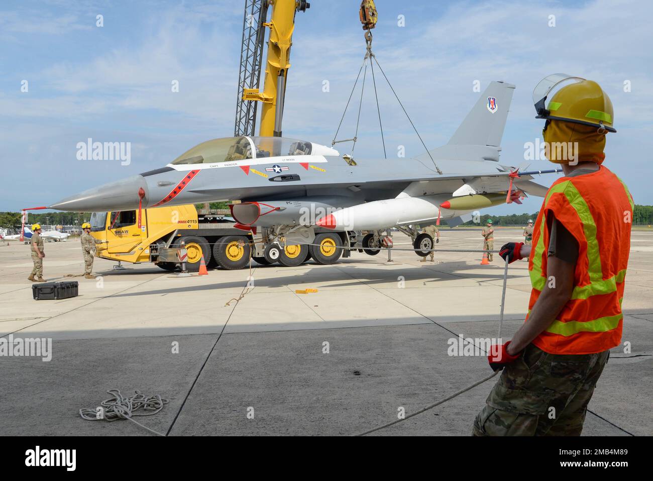 An Airmen assists in rotating a suspended F-16D fighter jet at a Crash ...