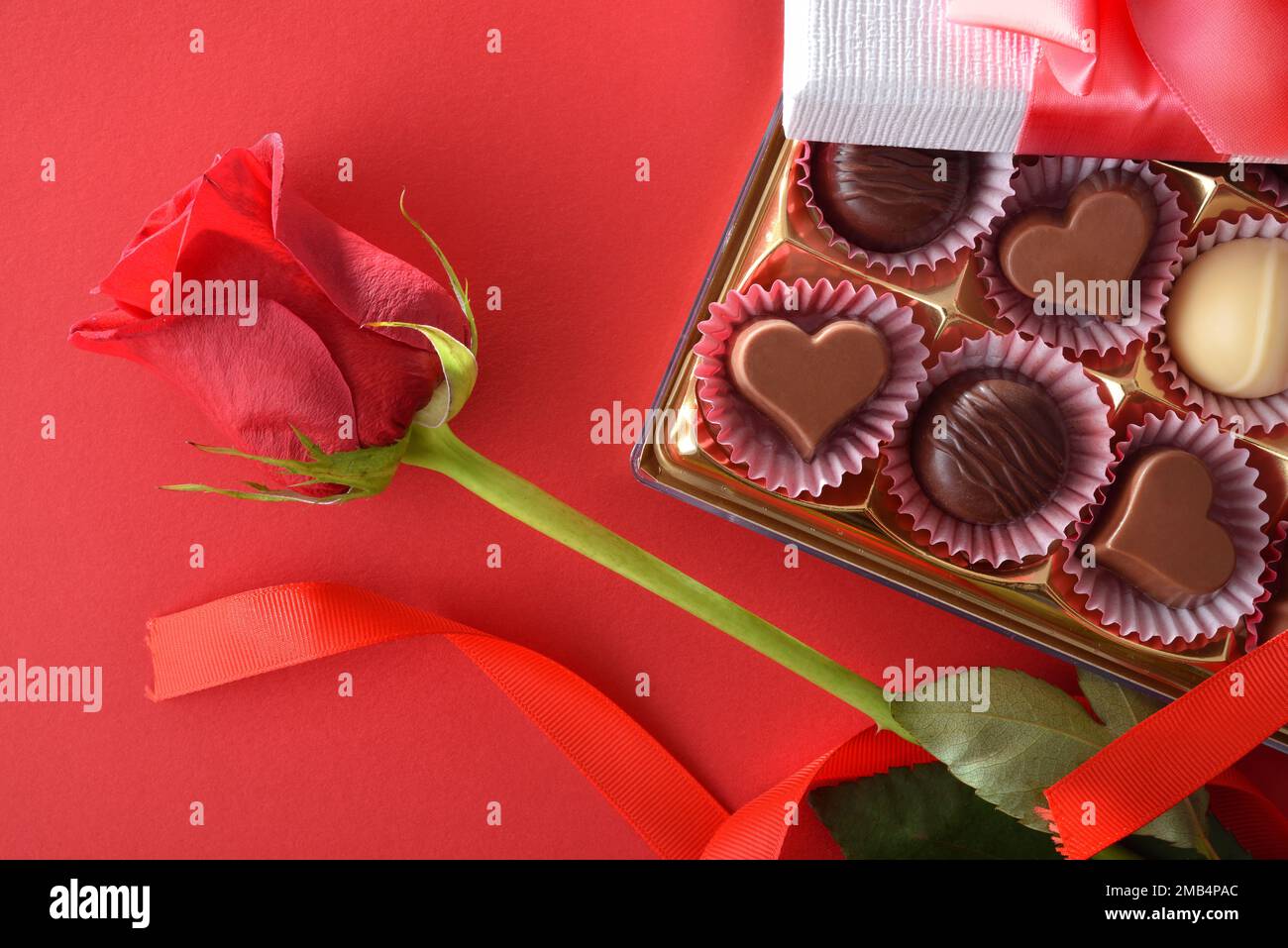 Gift detail of assorted chocolates and red rose on a red background ...