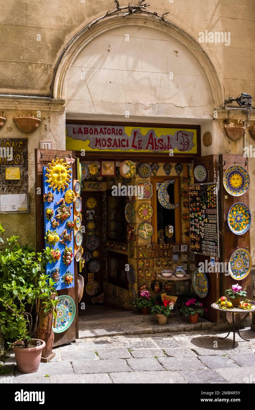 Many different colorful pottery souvenirs are offered for sale in a ...