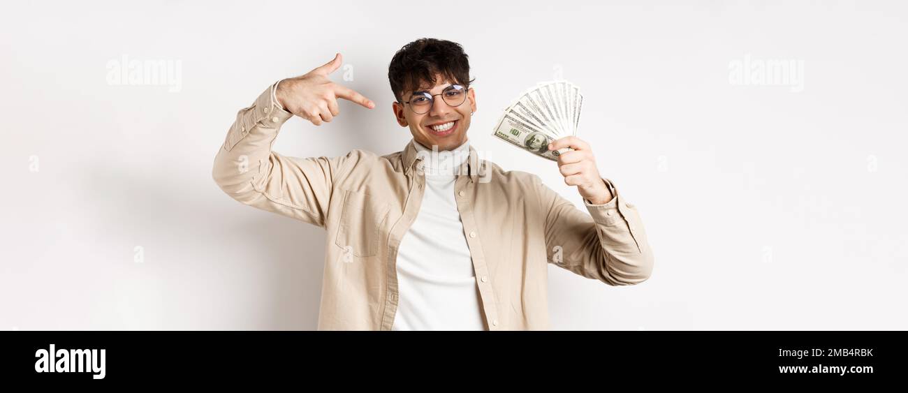 Cool handsome guy show-off, pointing at dollar bills and smiling ...
