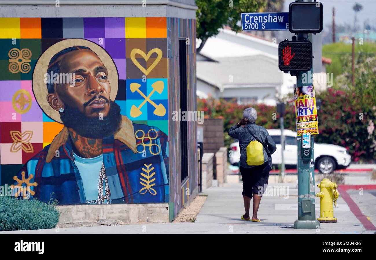 A pedestrian walks past of a mural of the late rapper Nipsey Hussle ...