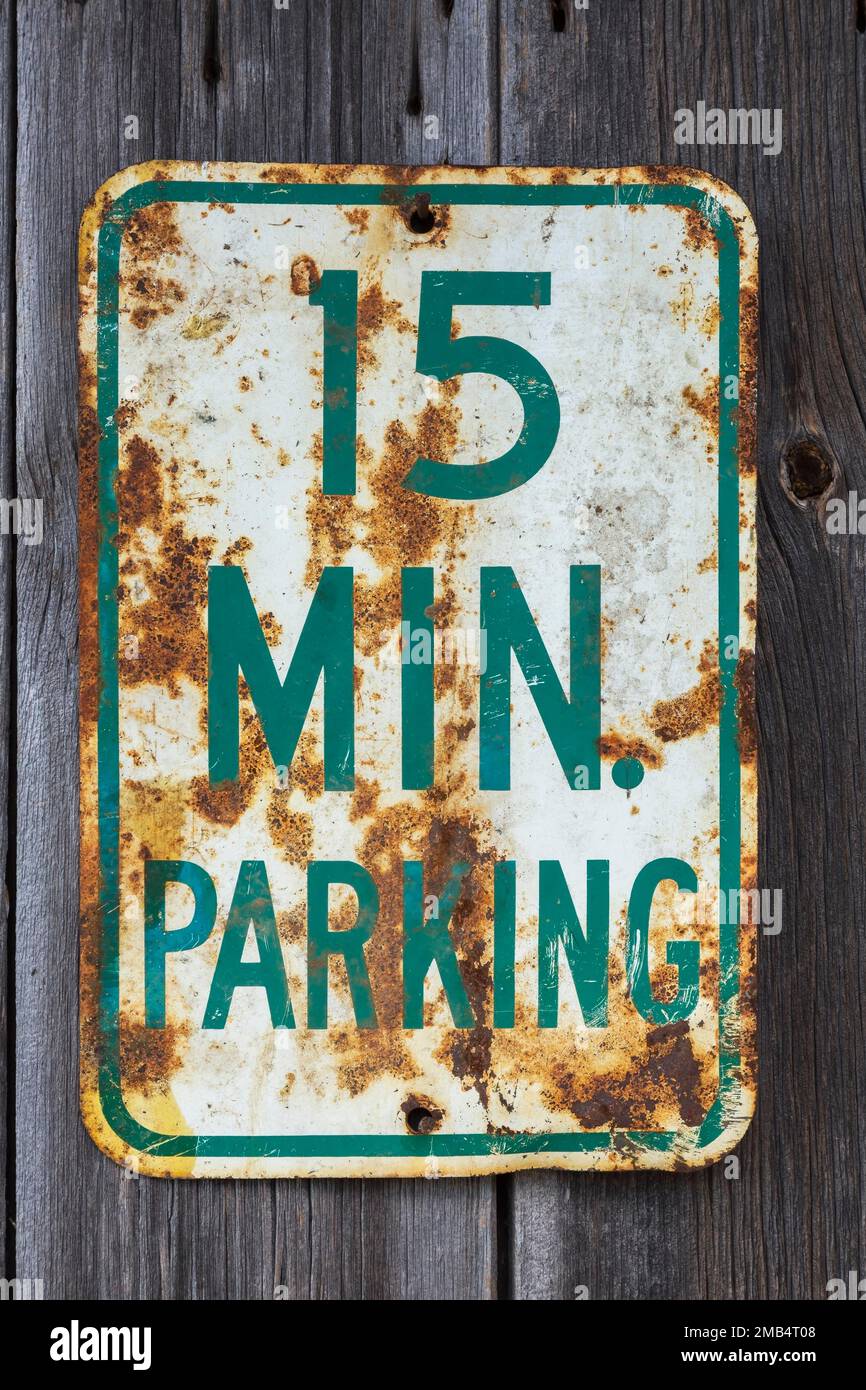 Old 15 minute parking sign displayed on side wall of wood plank storage ...