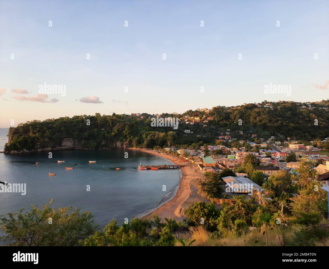 A high-angle shot of a coast full of buildings, boast, and green nature ...