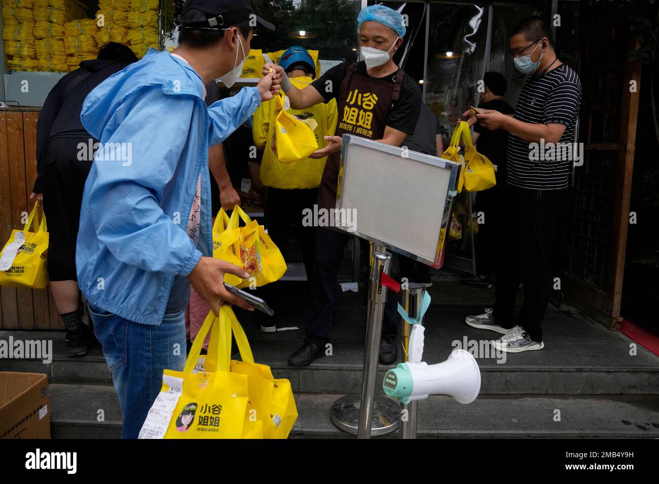 A restaurant worker hands over take-out orders to a delivery man ...