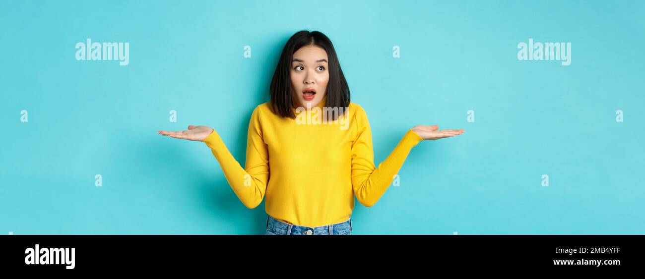 Confused and shocked asian woman dont understand, shrugging with spread ...