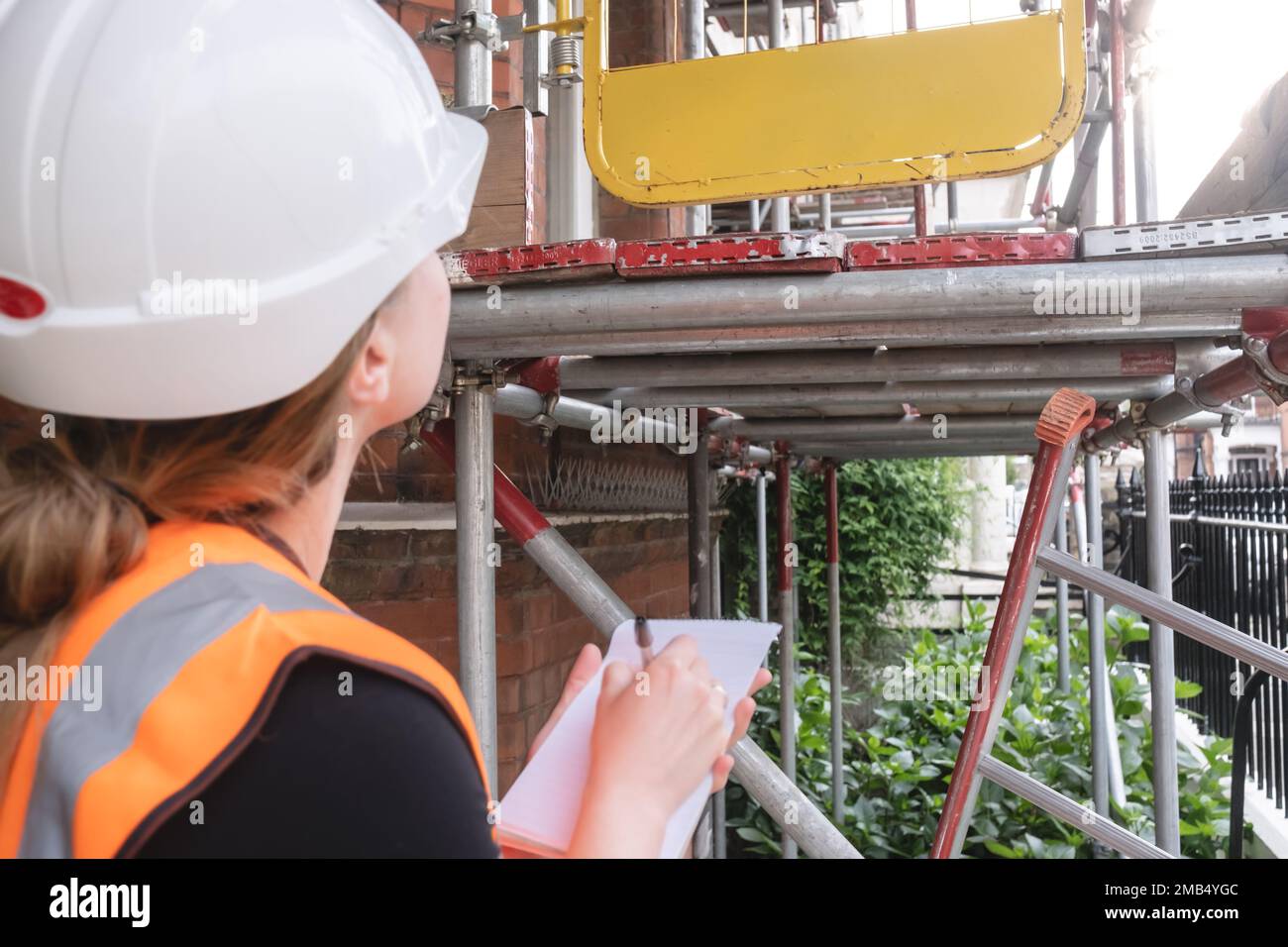 Photo with focus on scaffolding with unrecognizable female civil ...