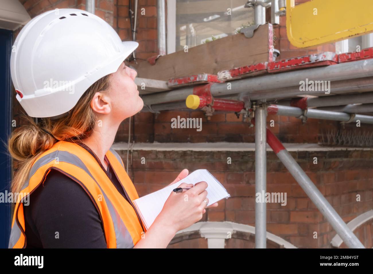 Female civil engineer looking up and checking a construction site ...