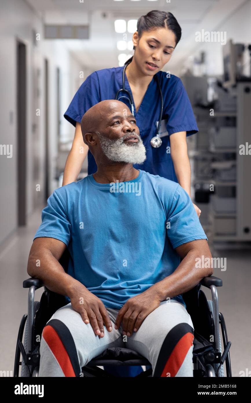 Vertical of diverse female doctor pushing senior male patient in ...