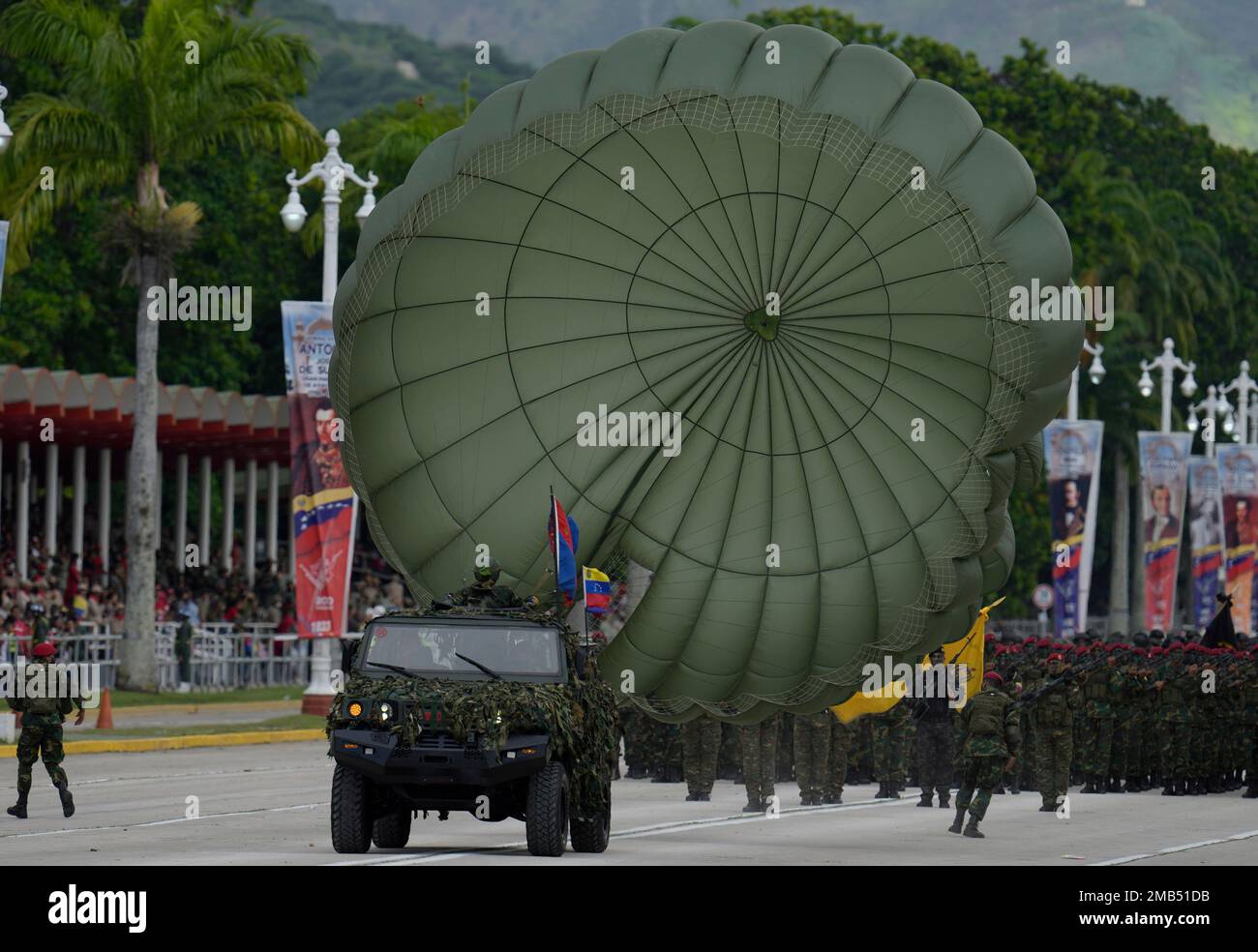 A military vehicle with a deployed parachute leads a parade marking ...