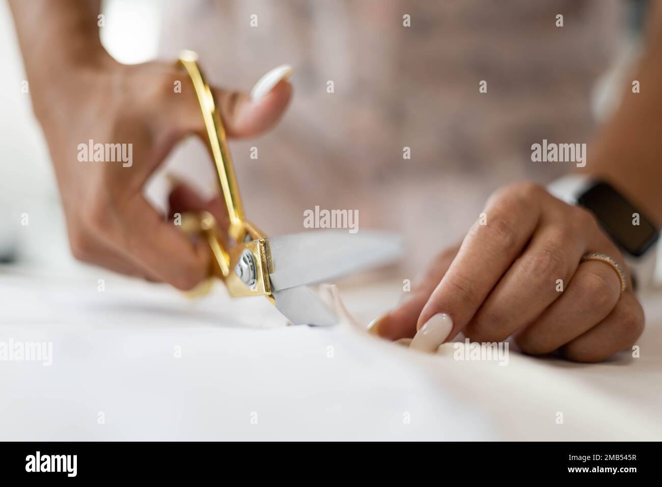 Closeup hands of female professional seamstress cutting textile use ...