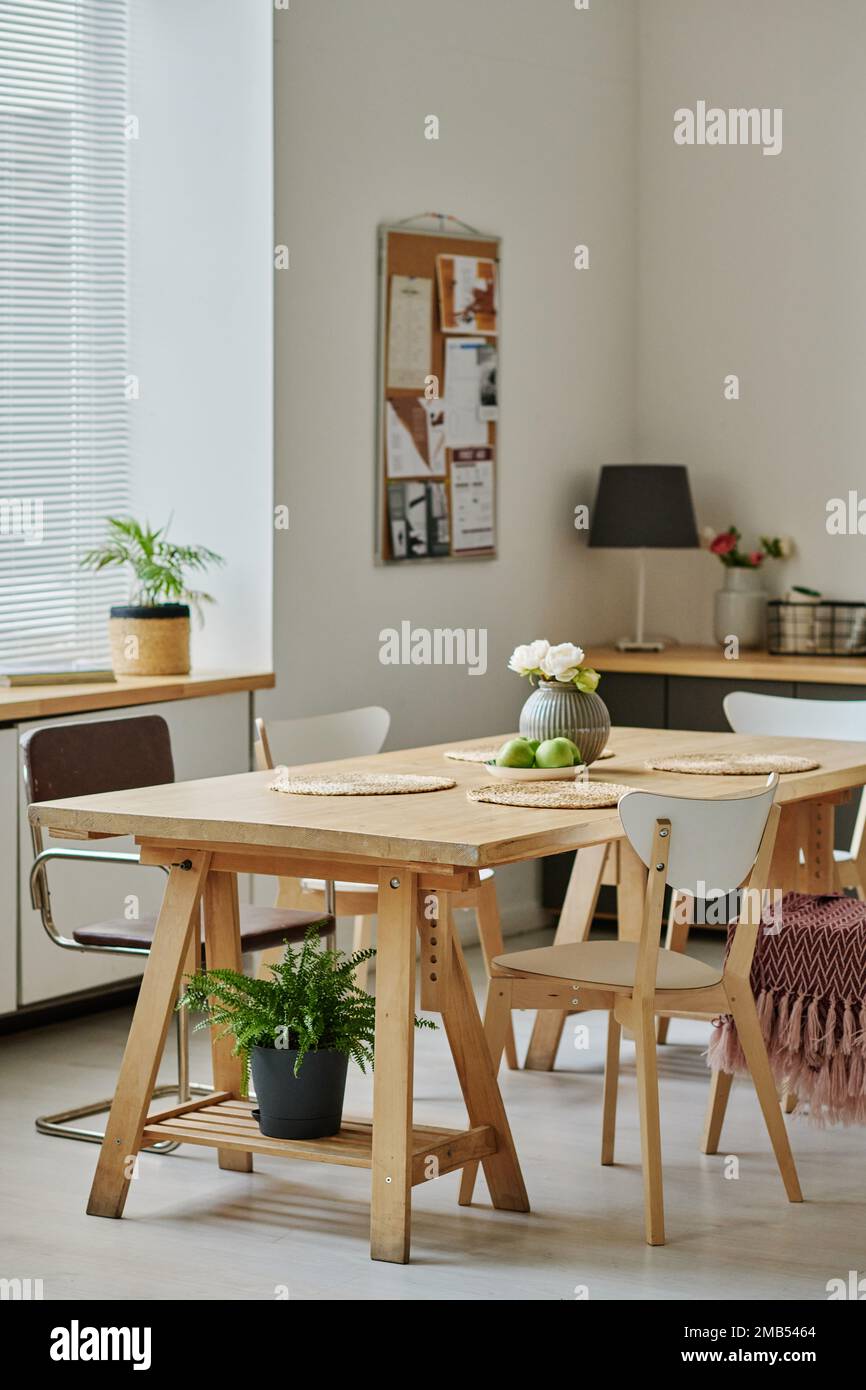 Vertical image of light modern kitchen with wooden dining table in the ...