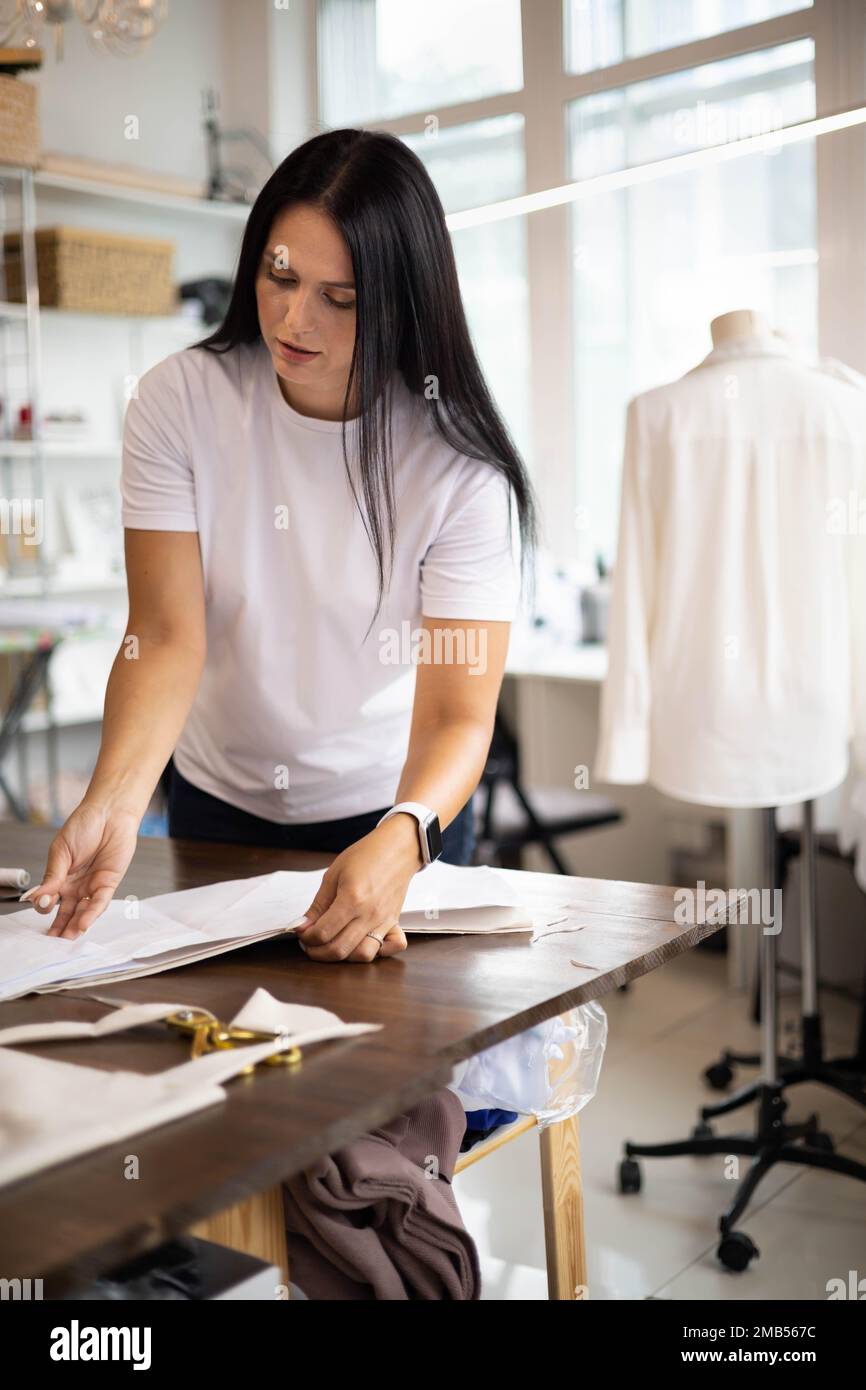 Modern woman tailor creating fashion clothes use paper pattern at ...