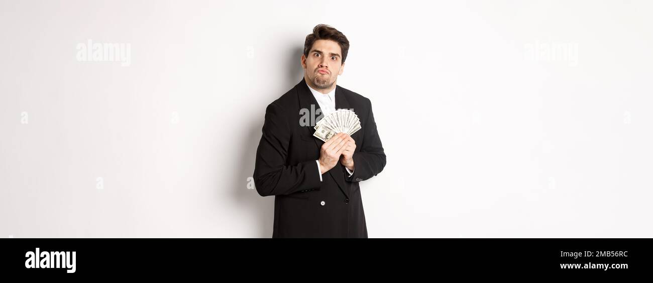 Image of greedy guy in black suit, holding money and unwilling to share ...