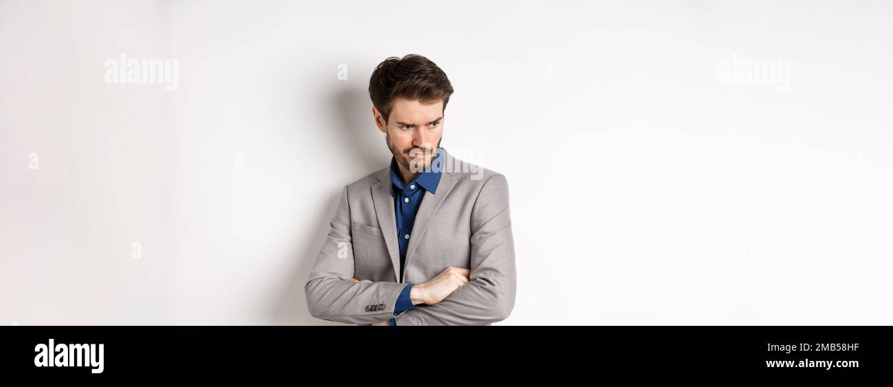 Moody guy in suit looking aside with unfair face, cross arms on chest ...