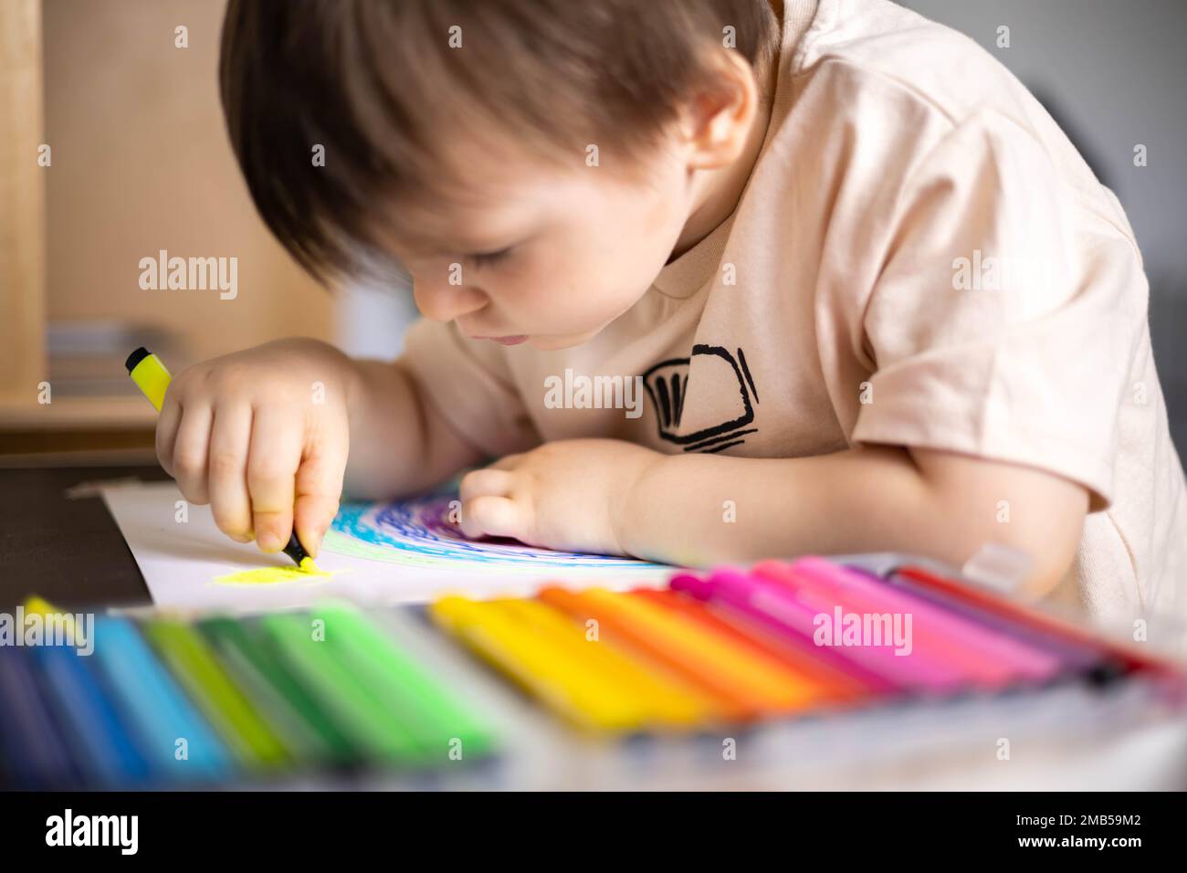 Enthusiastic male kid drawing multicolor rainbow paper sheet closeup ...