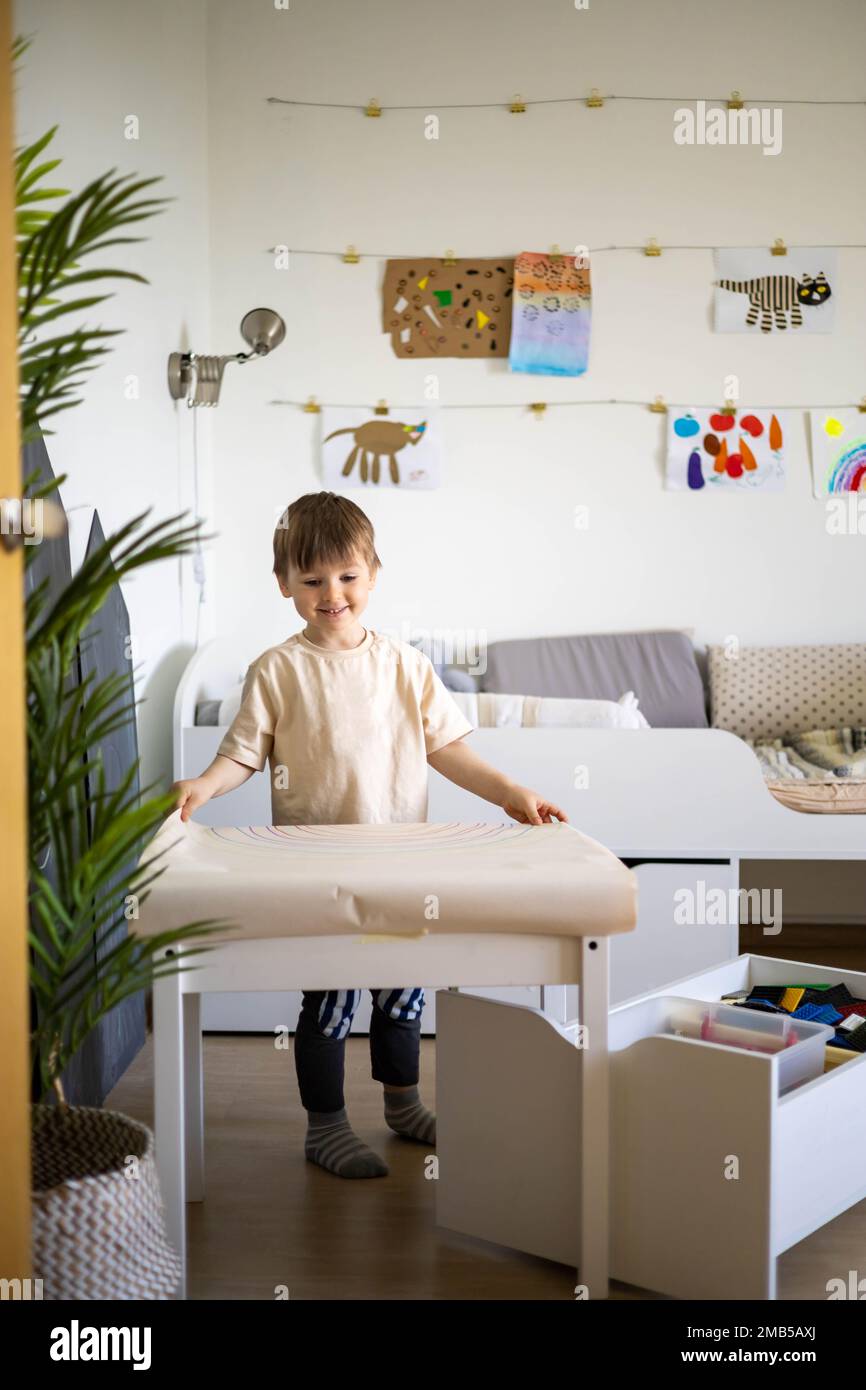 Smiling baby boy playing at cozy childish playroom interior with paper ...