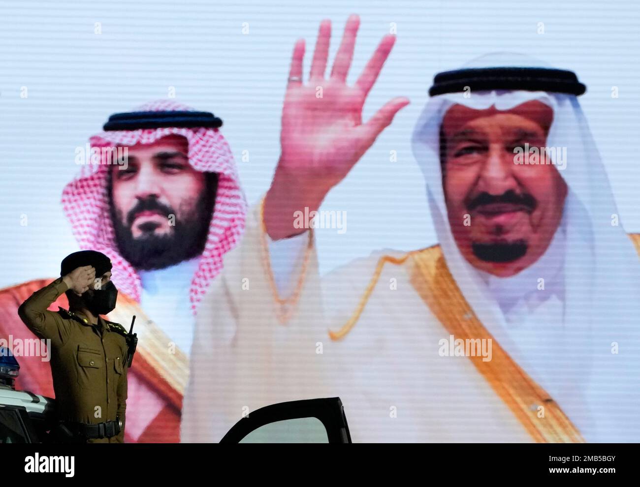 A Saudi policeman salutes in front of a screen displaying images of ...