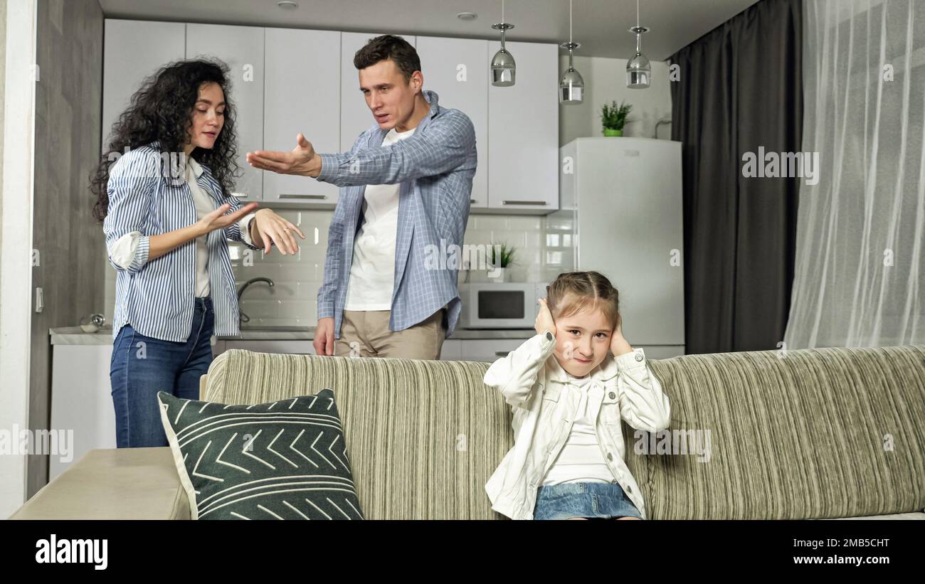 Junior schoolgirl sits closing ears against arguing parents Stock Photo ...