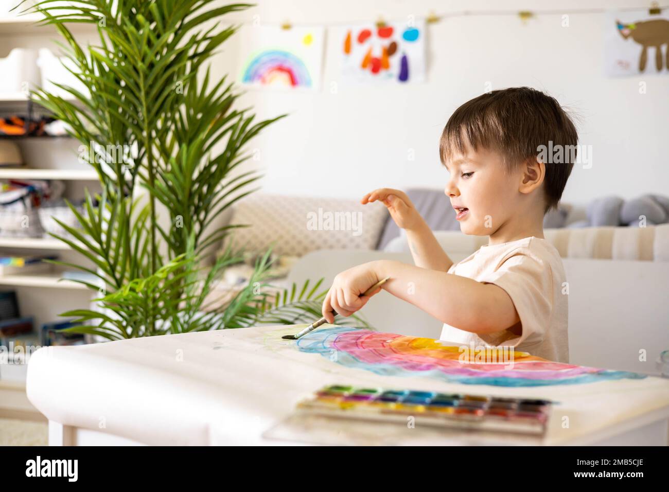 Confident cute male kid art drawing multicolored rainbow arch use ...