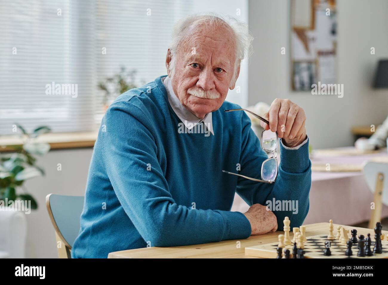 Portrait of senior man with grey hair looking at camera while playing ...