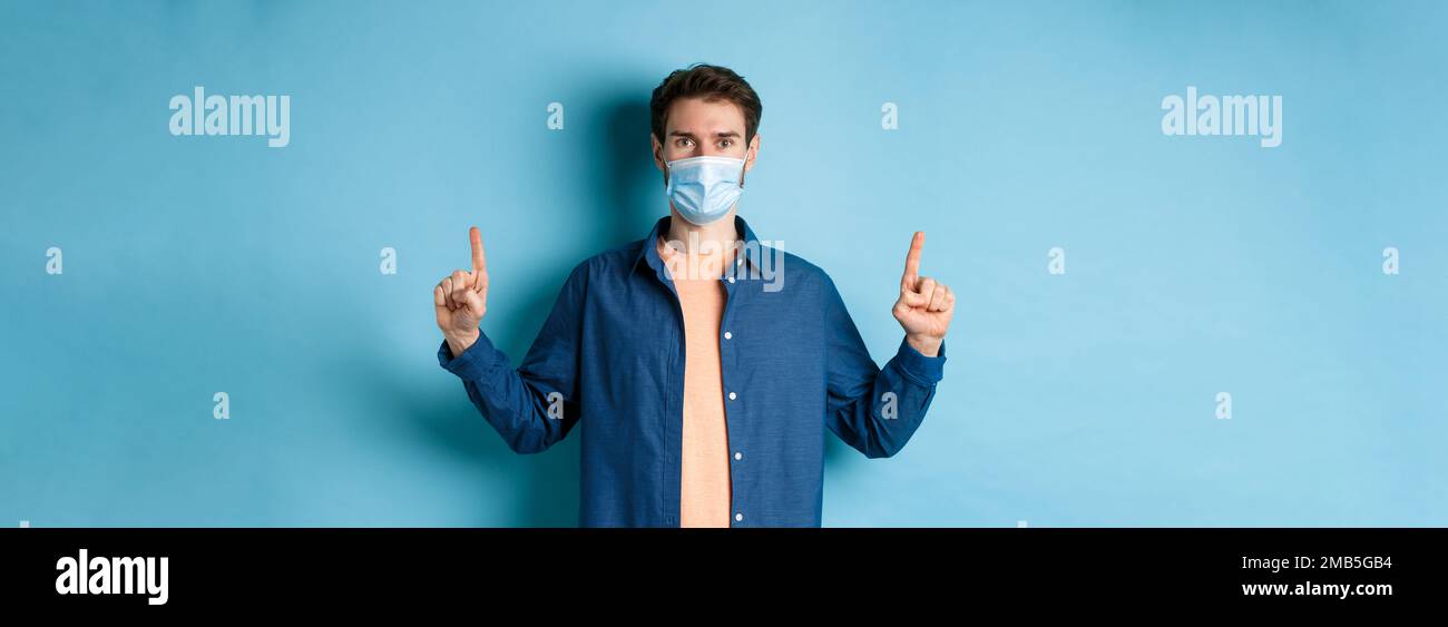 Covid-19 and lifestyle concept. Handsome young man in face mask looking ...