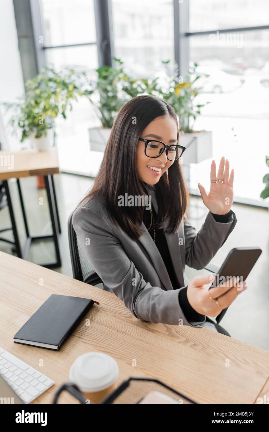 Cheerful asian interior designer having video call on smartphone in ...