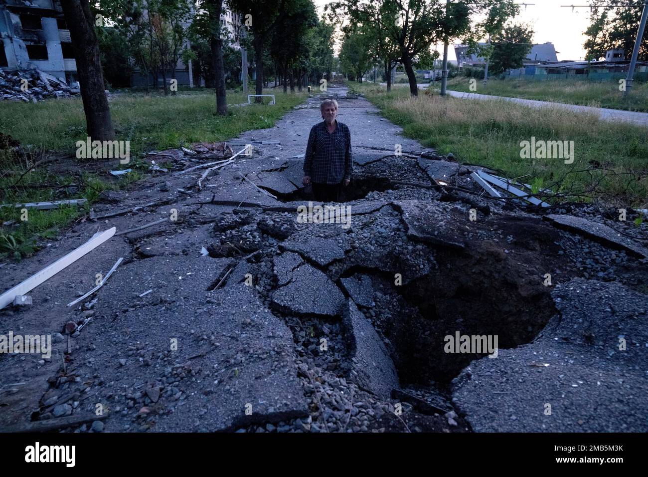 Viktor Shevchenko stands in a crater to show how deep it was that created by a shell after a ...