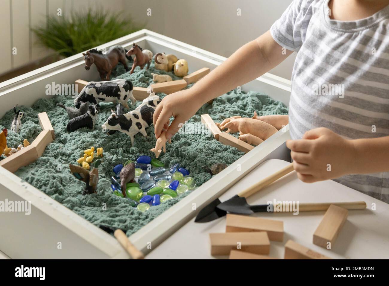Cute baby boy playing sensory box kinetic sand table with farm animals ...