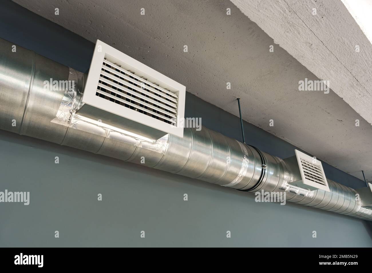 Silver ventilation pipes hanging from the ceiling inside the building ...
