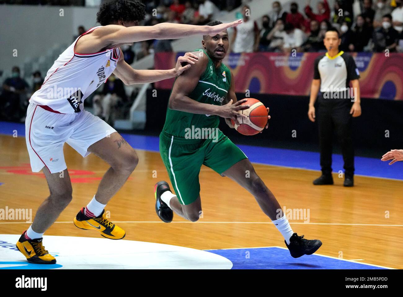 Saudi Arabia's Mathna Almarwani, right, drives past Indonesia's Derrick ...