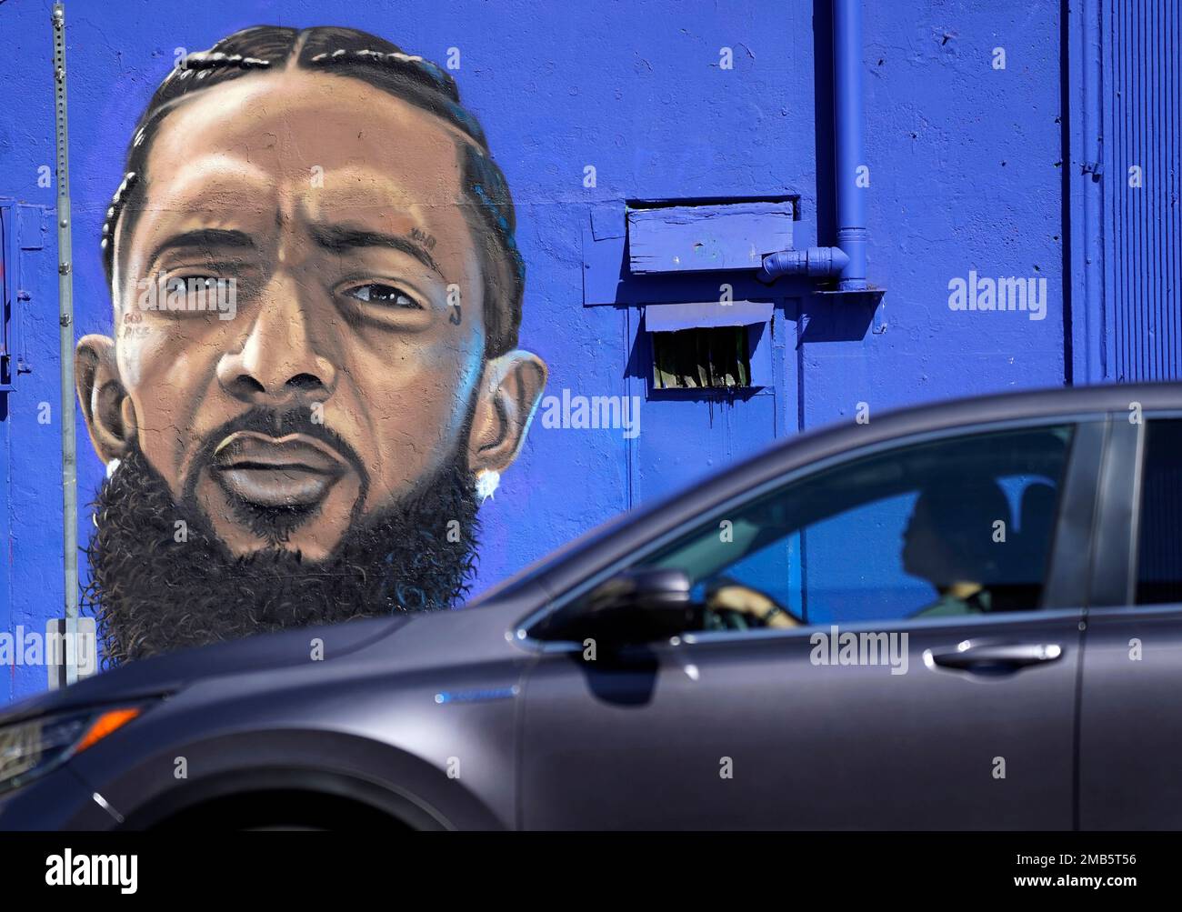 A motorist drives past a street mural of the late rapper Nipsey Hussle ...